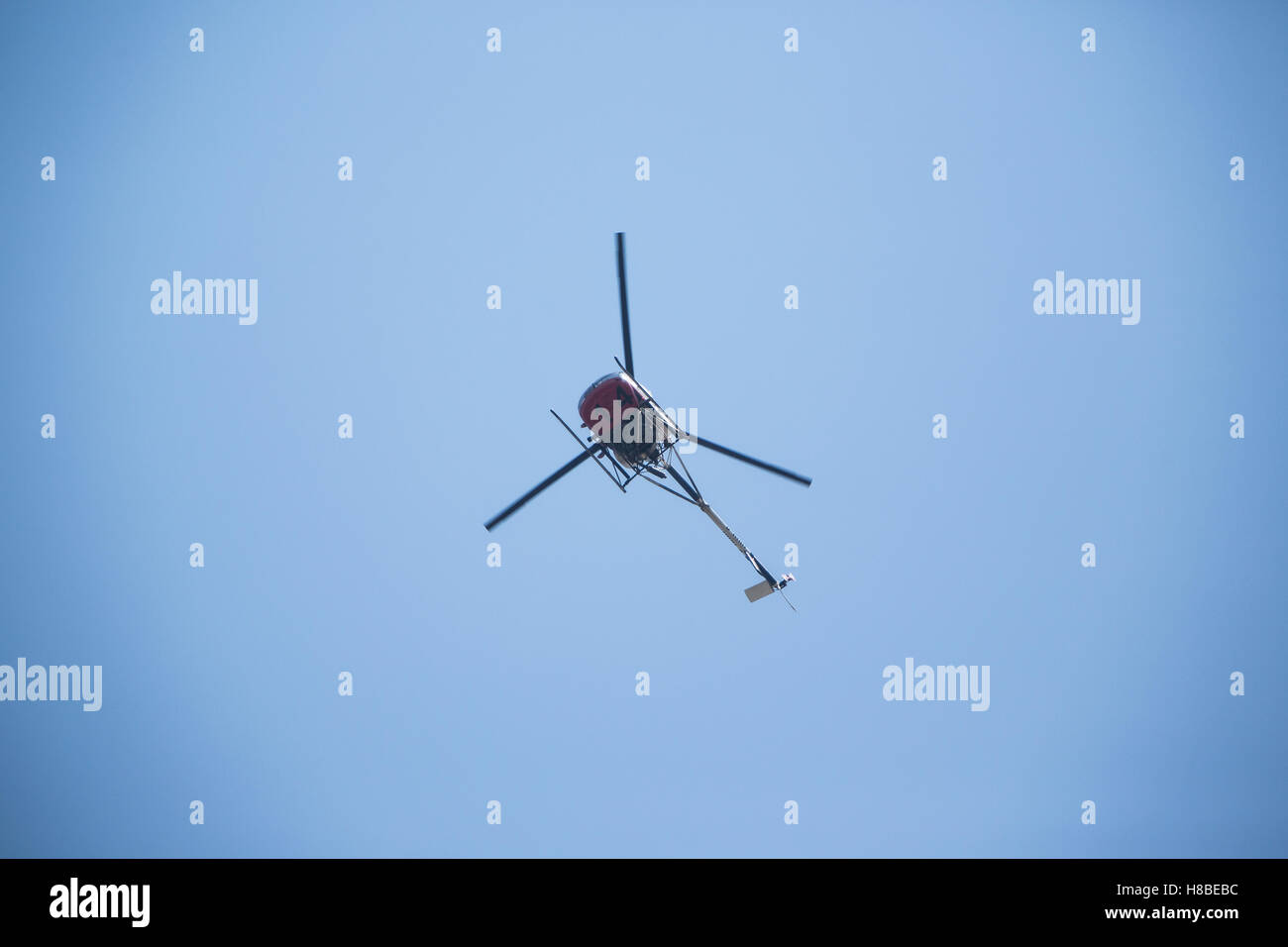 Flying helicopter seen from below in a bright blue sky Stock Photo - Alamy