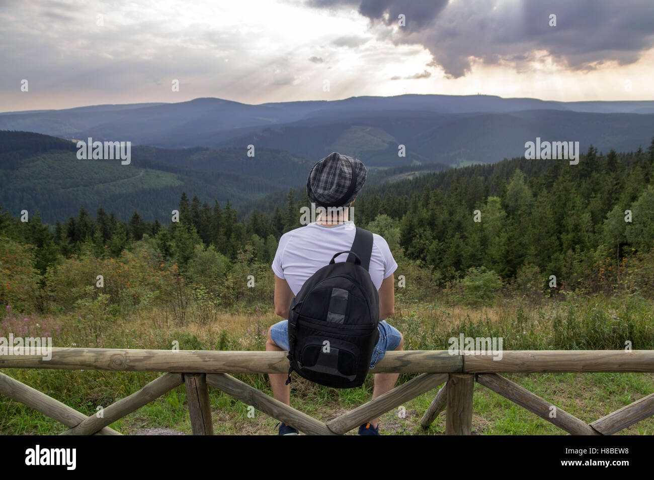 Young man looking at a mountain landscape on fence. Rear view Stock ...