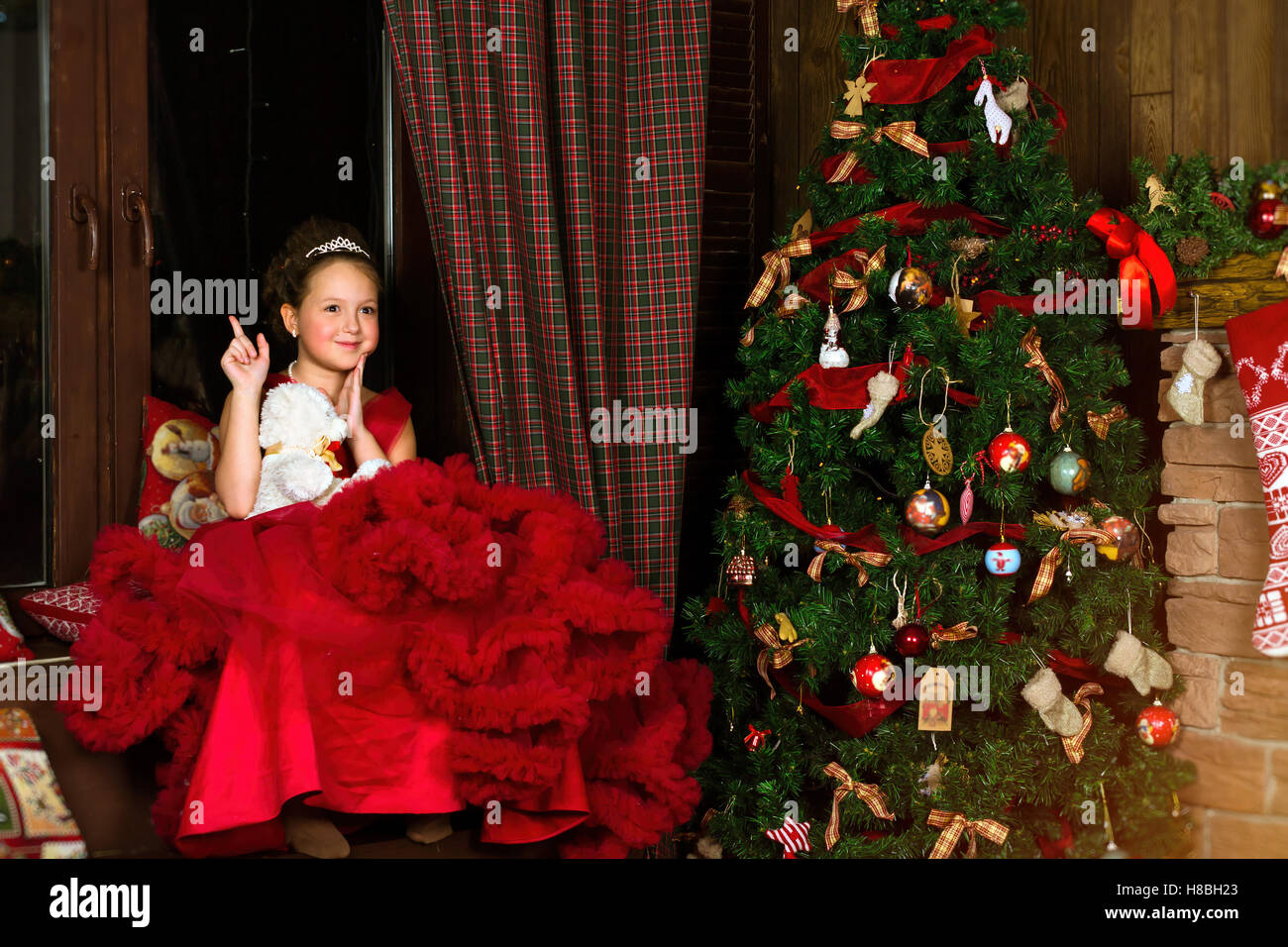 Little winter Princess - girl in red dress, sitting on windowsill and ...