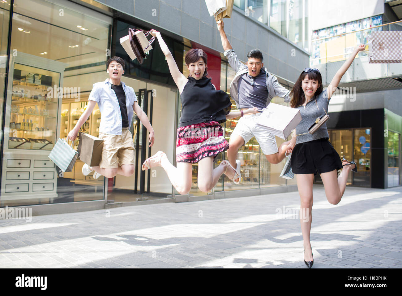 Happy young Chinese friends jumping with shopping bags Stock Photo - Alamy