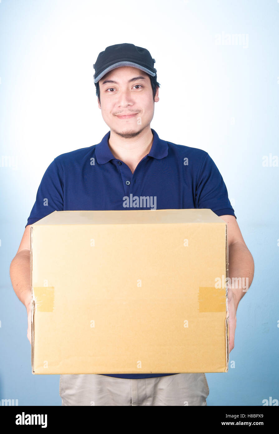Smiling handsome asian delivery man wearing cap, giving and carrying ...