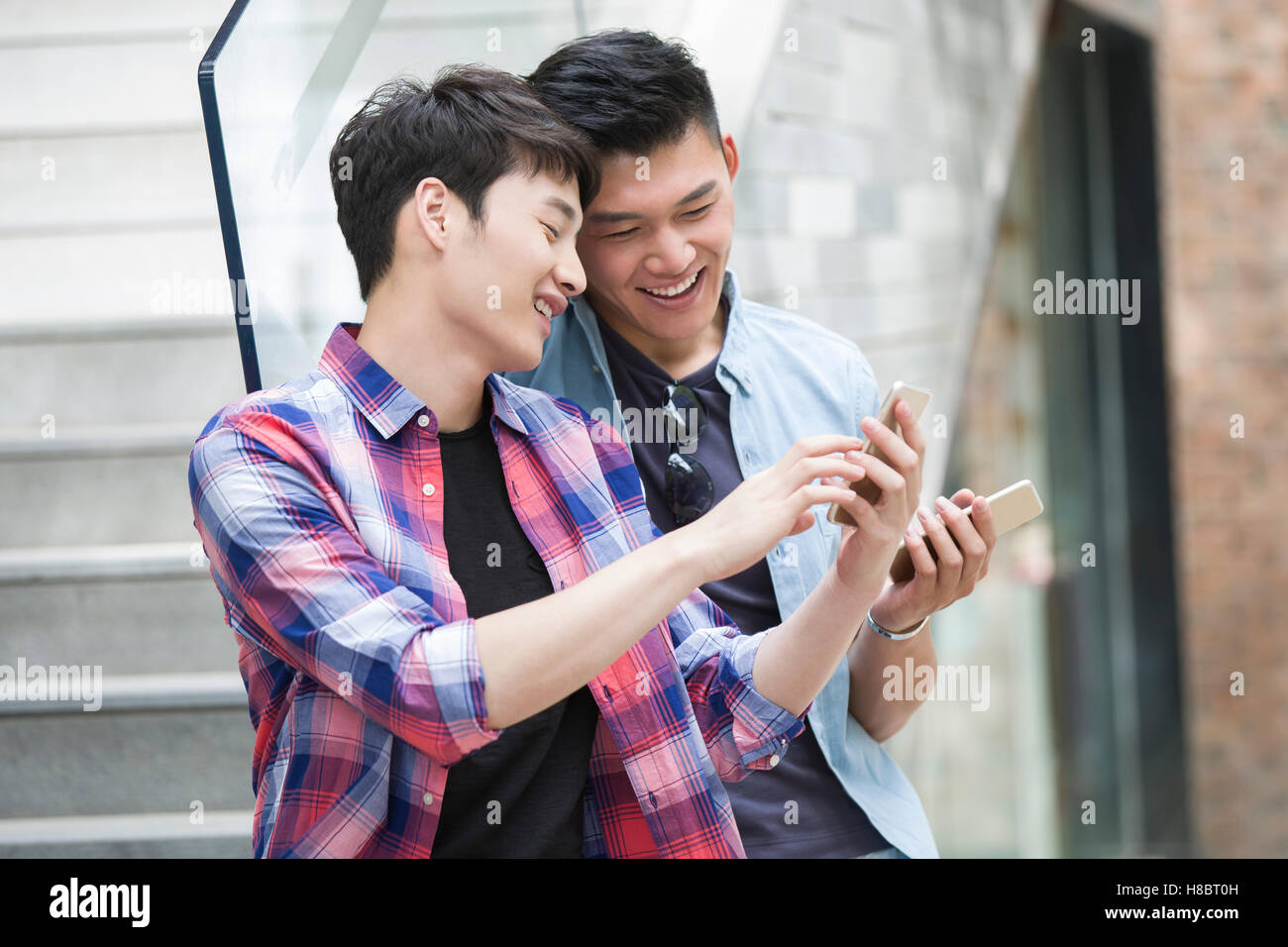 Young Chinese friends looking at a smart phone Stock Photo - Alamy