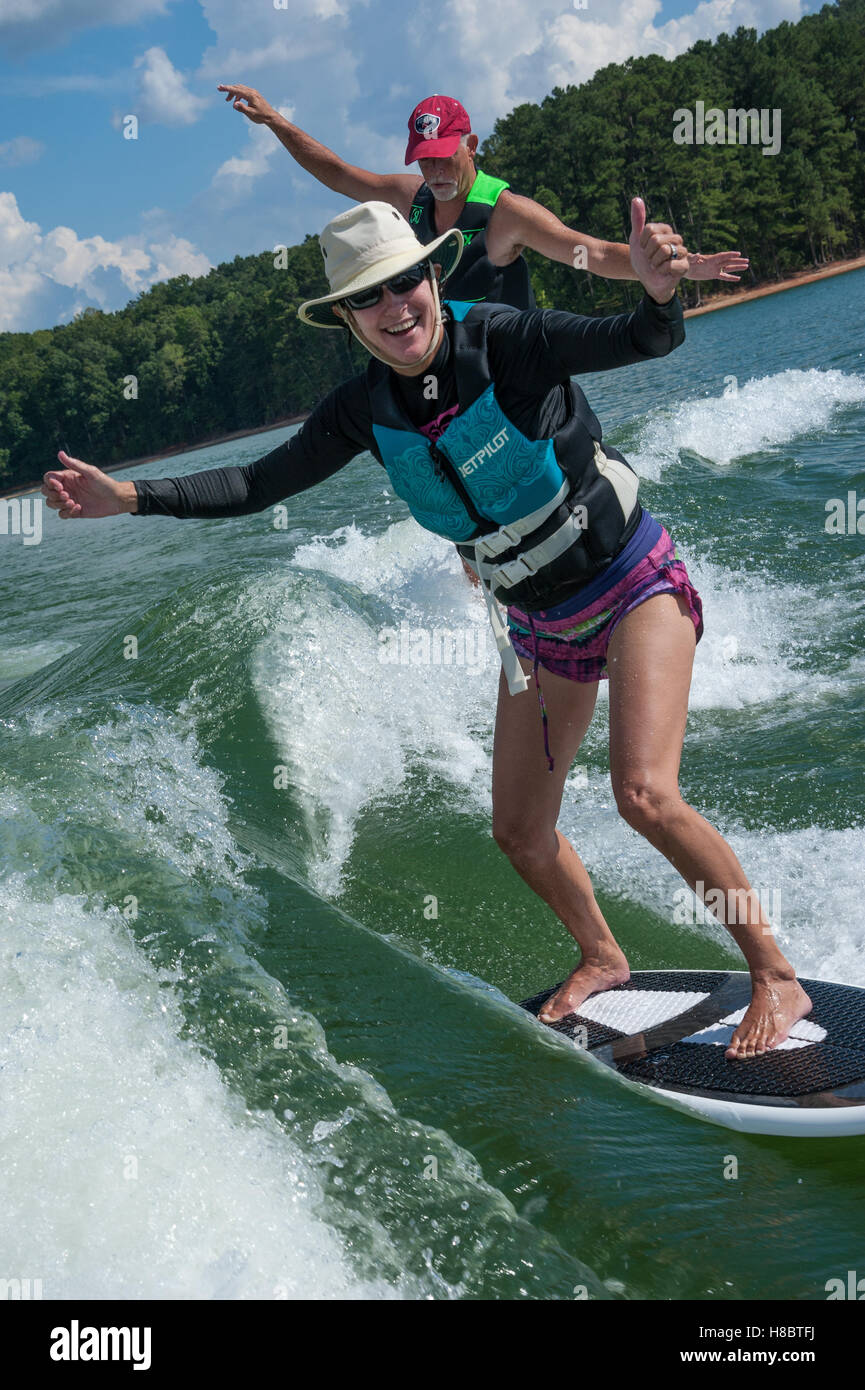 Senior couple enjoying active lifestyle of wake surfing together in ...