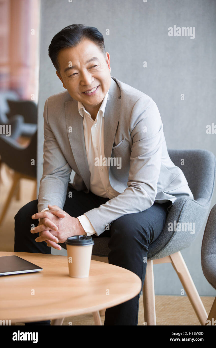 Happy Chinese businessman sitting in office Stock Photo - Alamy