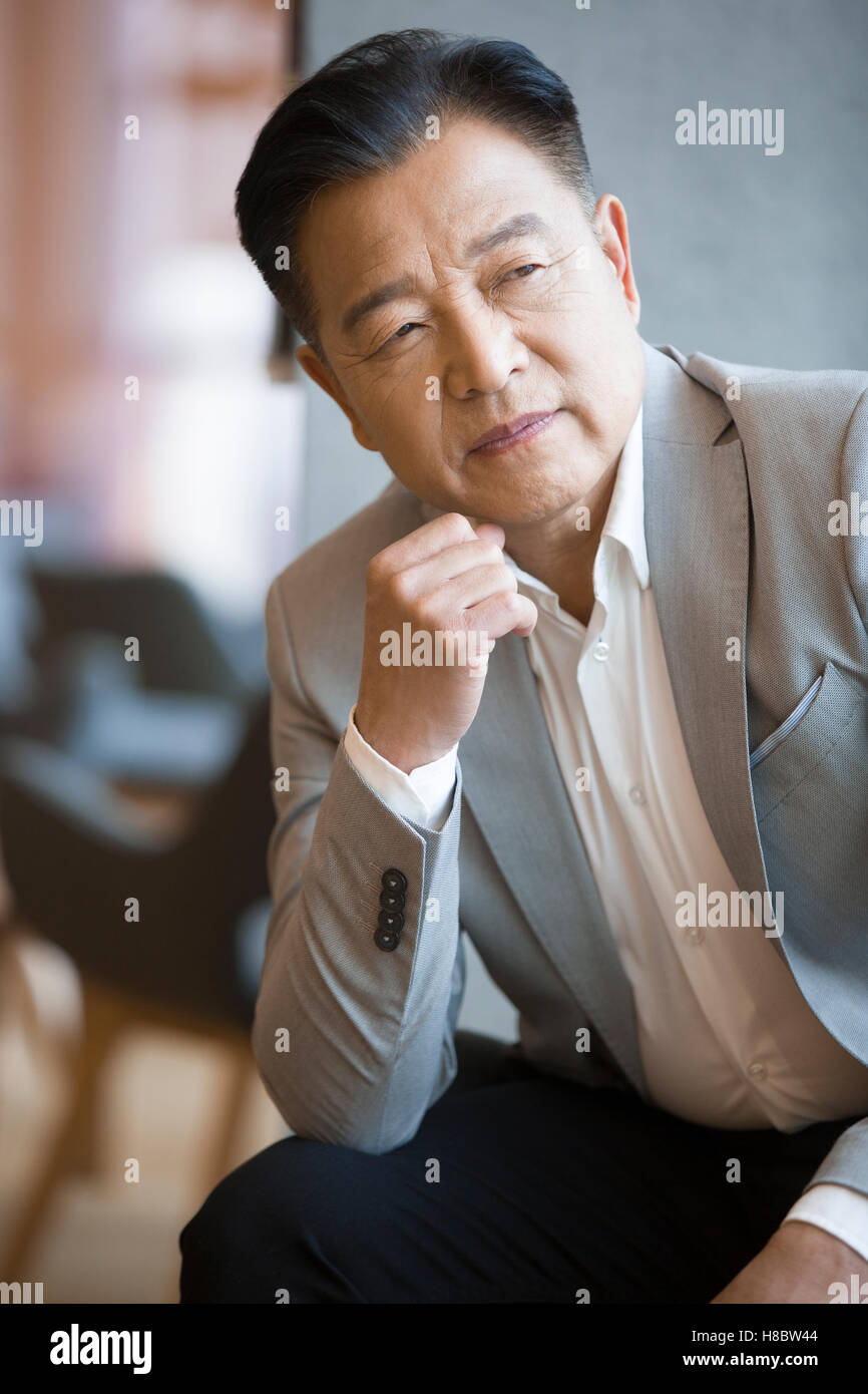 Confident Chinese businessman thinking in office Stock Photo - Alamy