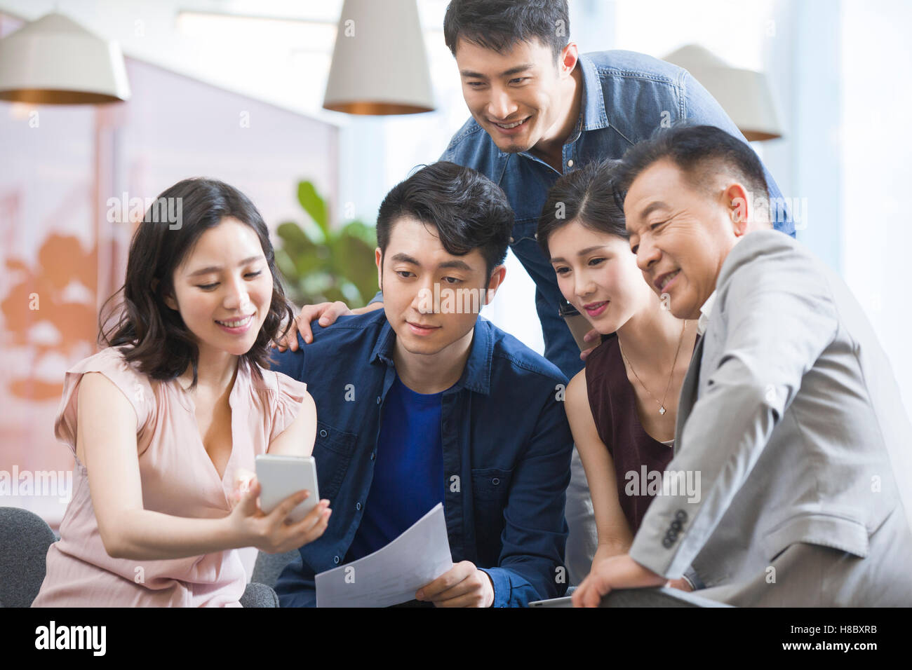 Chinese businesswoman showing smart phone to colleagues Stock Photo - Alamy