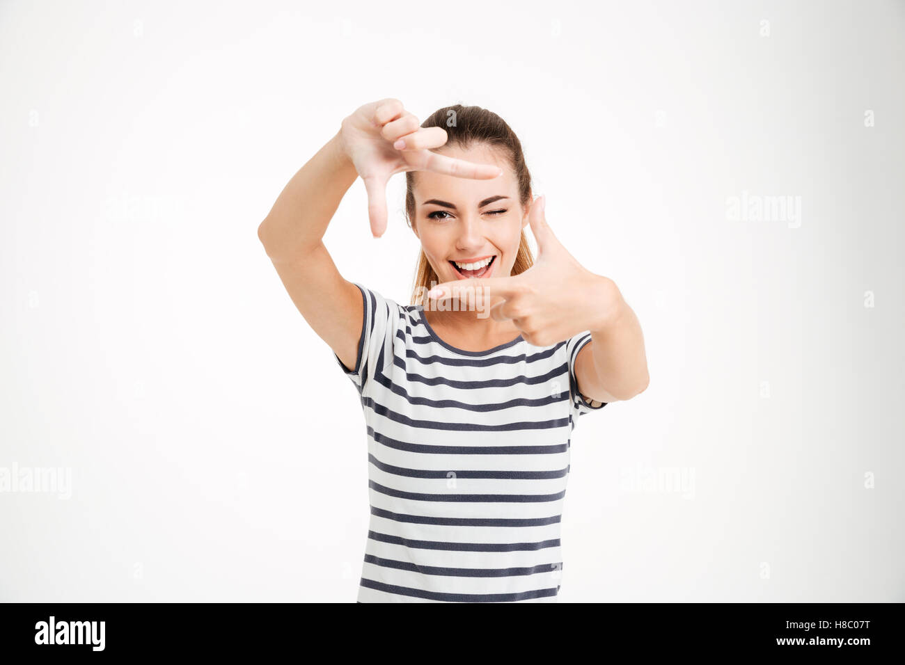 Happy smiling woman making frame with fingers and winking isolated on a ...