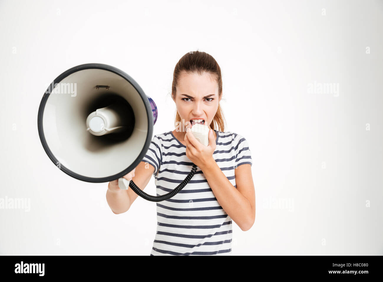 Beautiful woman shouting into megaphone isolated on a white background ...