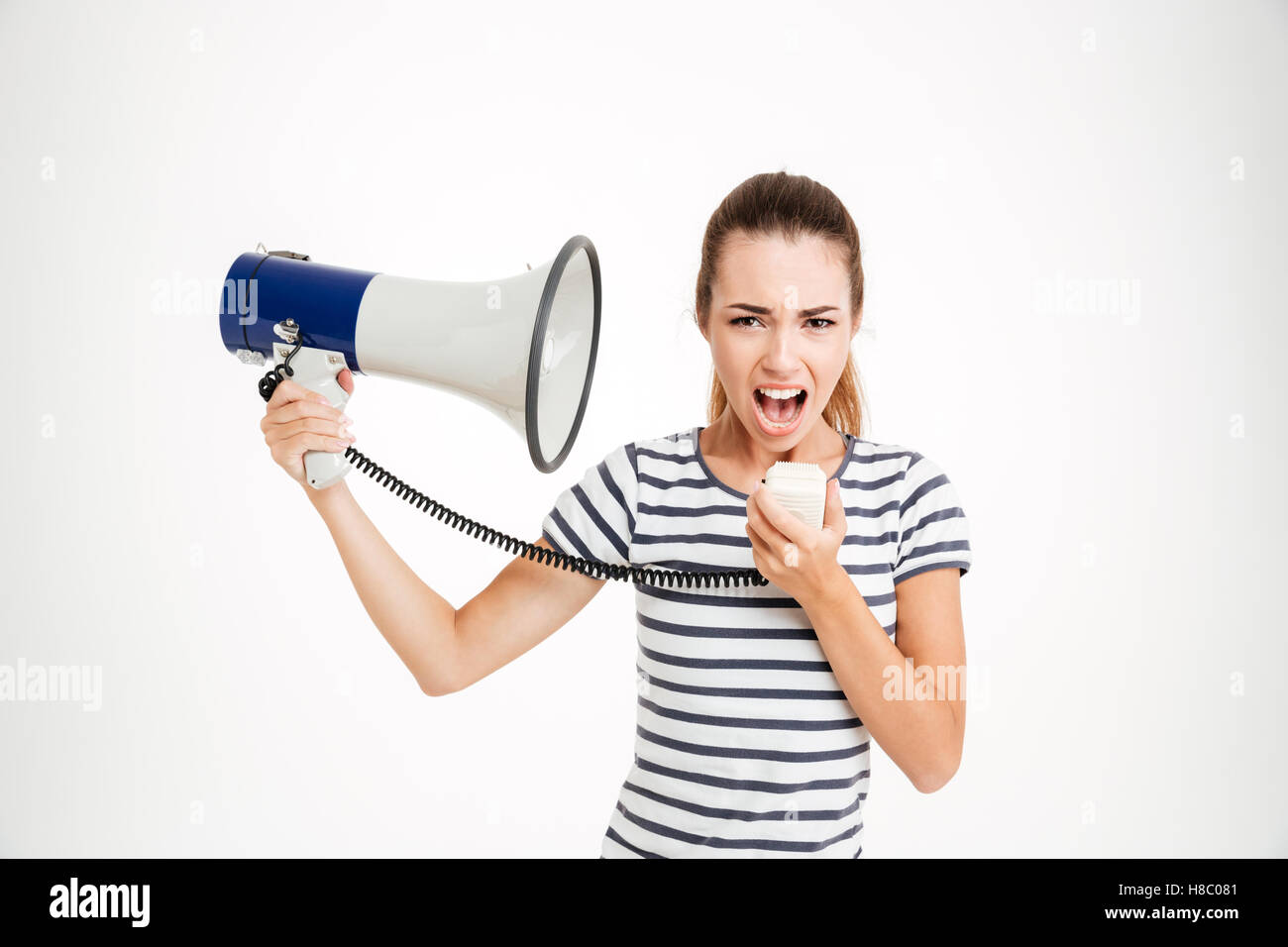 Young woman shouting into loudspeaker isolated on a white background ...