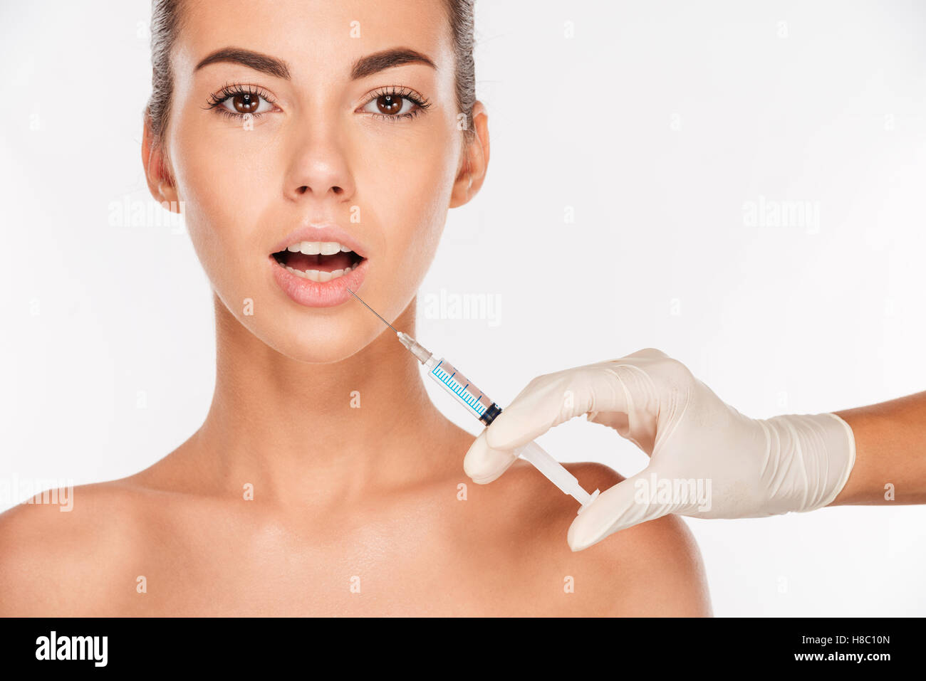 Scared young woman looking having beauty injection with syringe ...