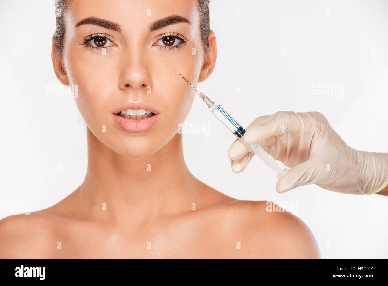 Close up of a beautiful young woman gets beauty injection in eye area ...