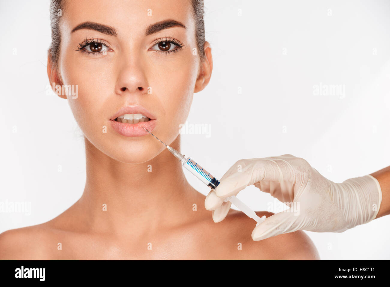Beautiful young woman gets beauty injection in lips with syringe ...