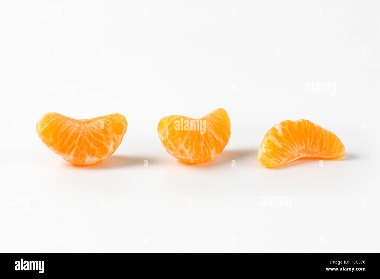 three separated segments of tangerine on white background Stock Photo ...