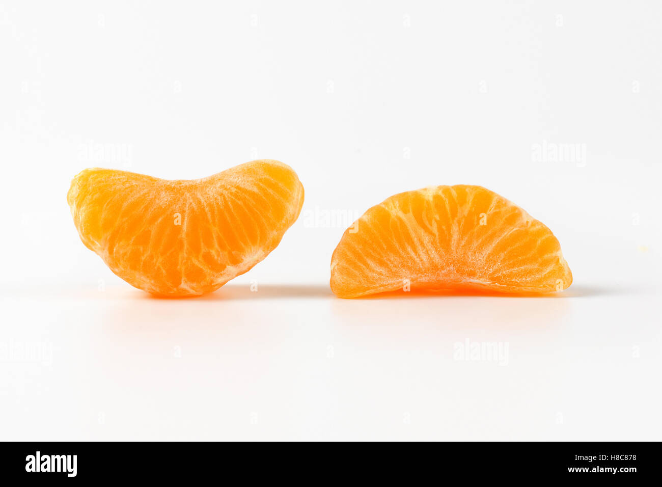 two separated segments of tangerine on white background Stock Photo - Alamy