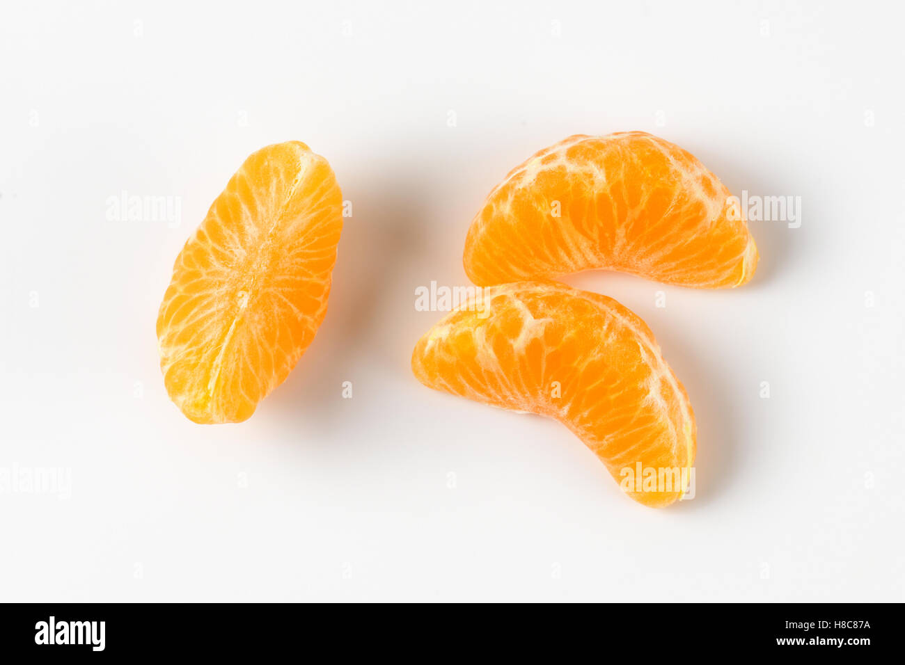 three separated segments of tangerine on white background Stock Photo ...
