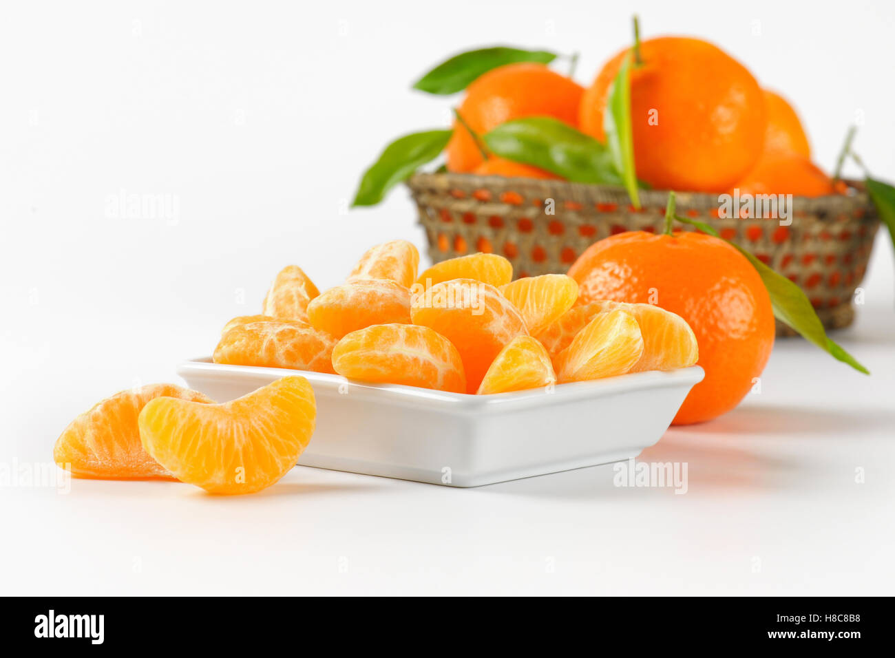 bowl of tangerine segments and whole tangerines on white background ...