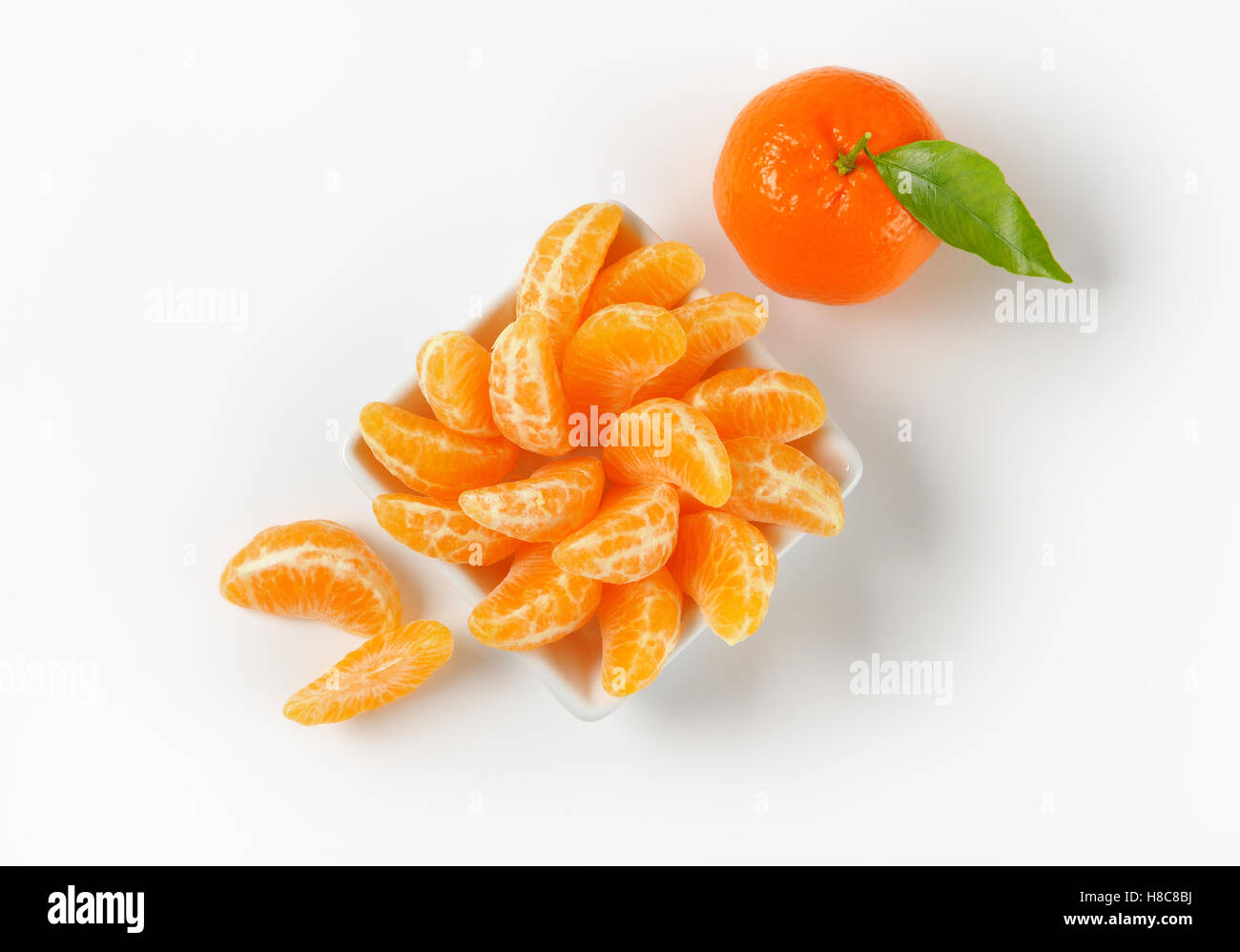 bowl of tangerine segments and whole tangerine on white background ...