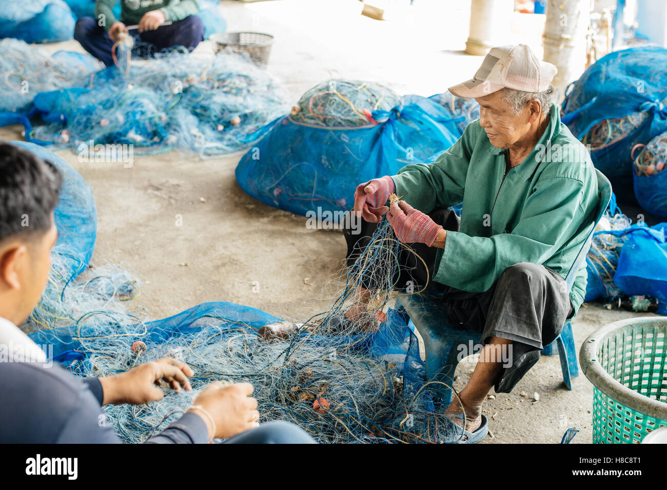 Thai people collect catch of sea food from fishing net in a village ...