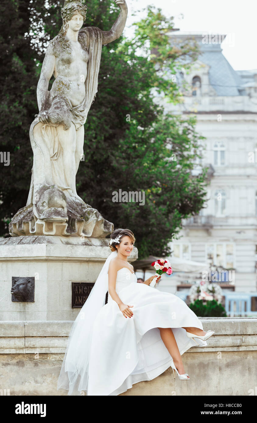 Bride sitting near monument Stock Photo - Alamy