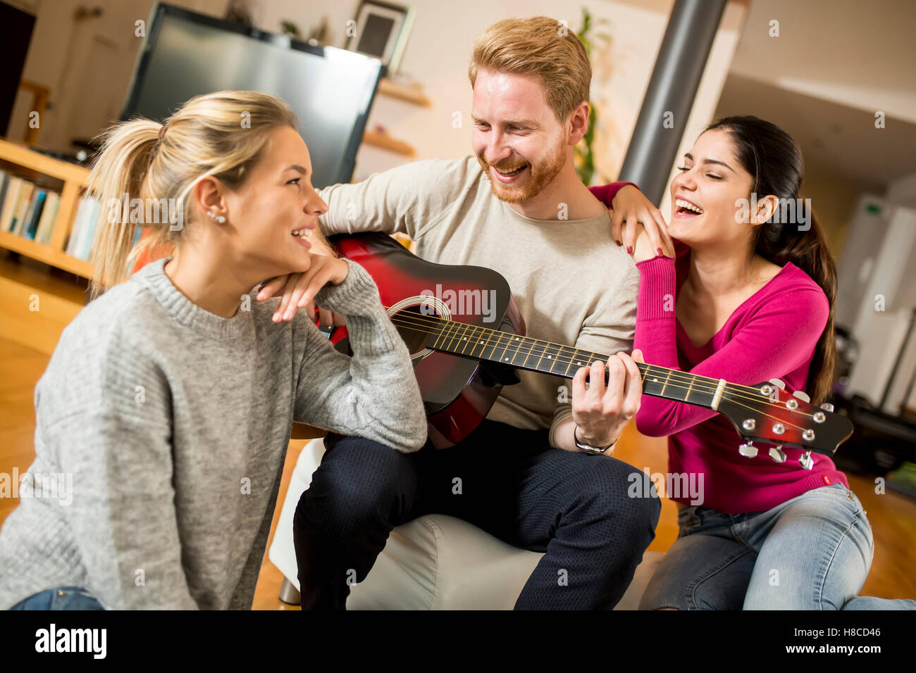 Happy friends playing guitar and listening to music at home Stock Photo ...