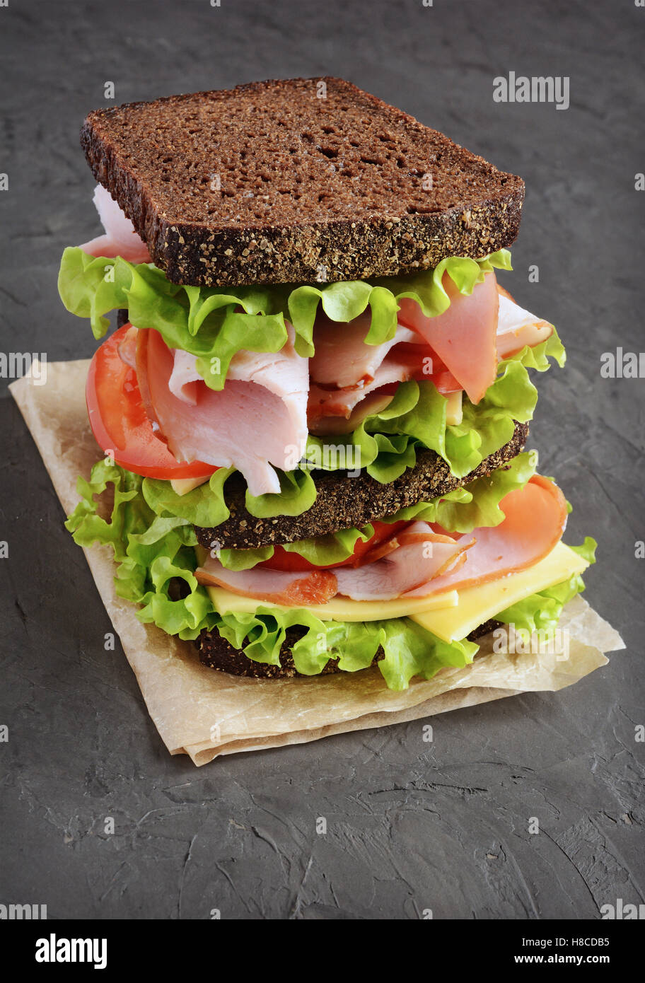 Sandwich with rye bread, ham, tomato, cheese and lettuce on black ...