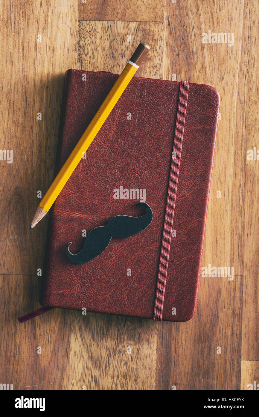 Fake black mustache on diary with pencil. Top view Stock Photo - Alamy