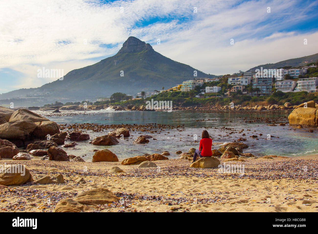 A female tourist sits on a rock at the beach enjoying the view at ...