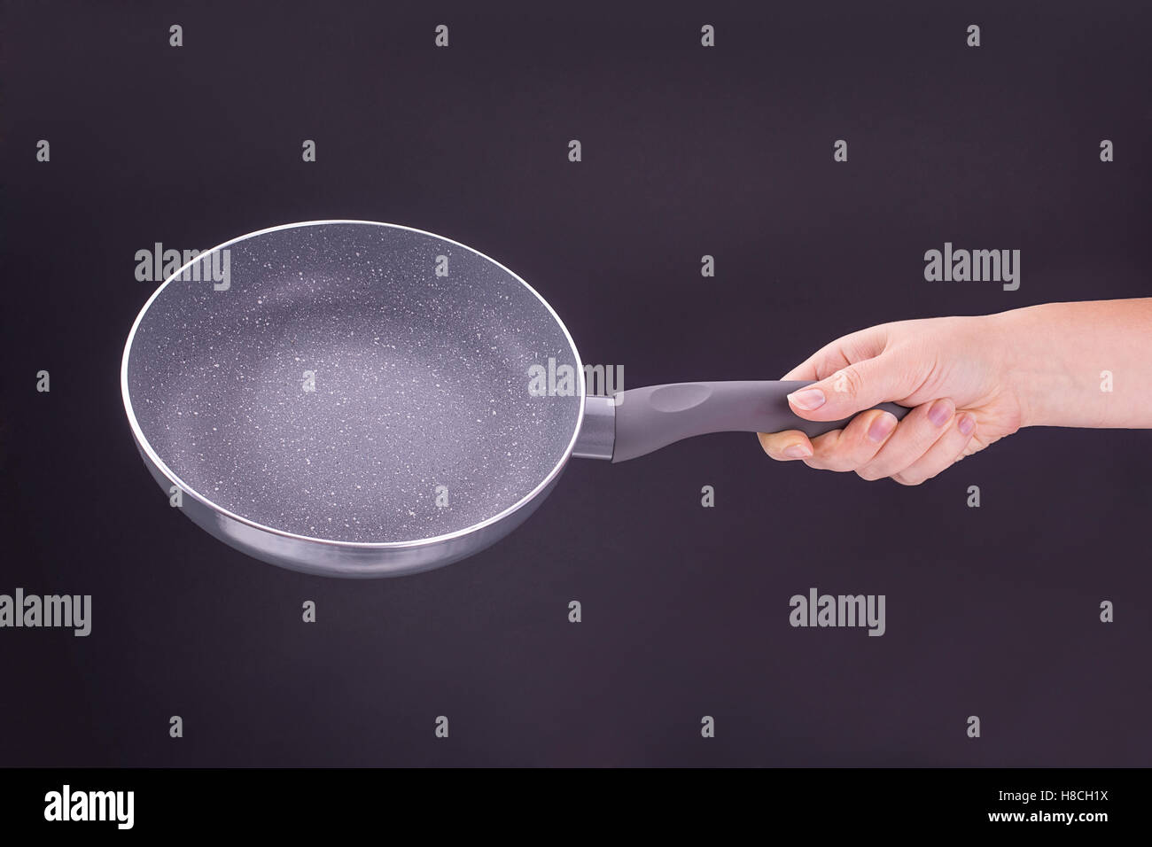 hand holding clean empty pan on a black background Stock Photo - Alamy
