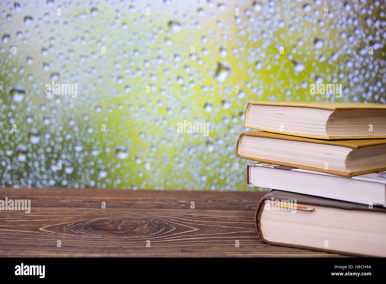 Books on an retro wooden table on a rainy day window background. Autumn ...