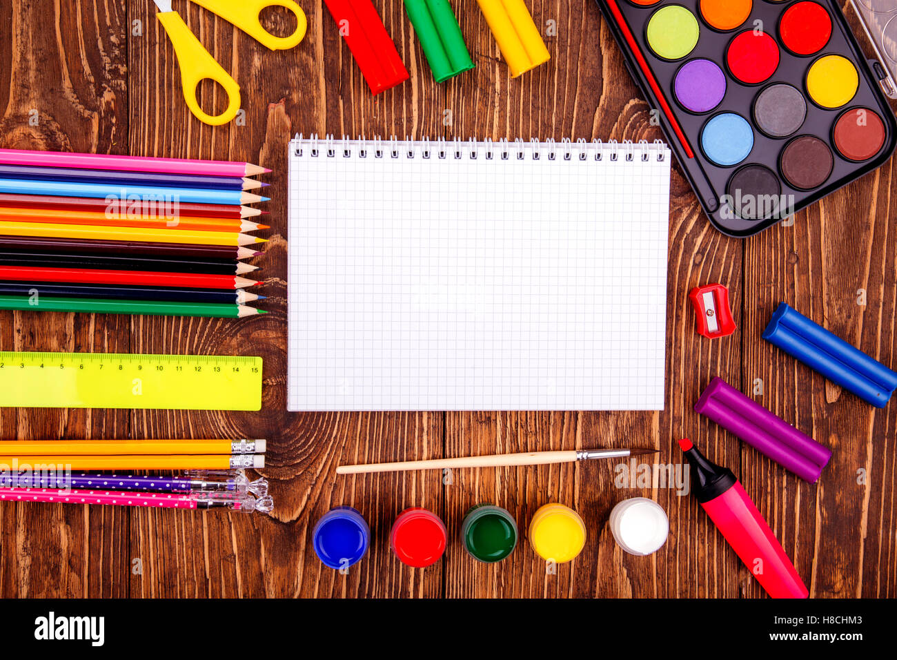 Opened blank notebook, frame of school supplies over a retro wooden ...
