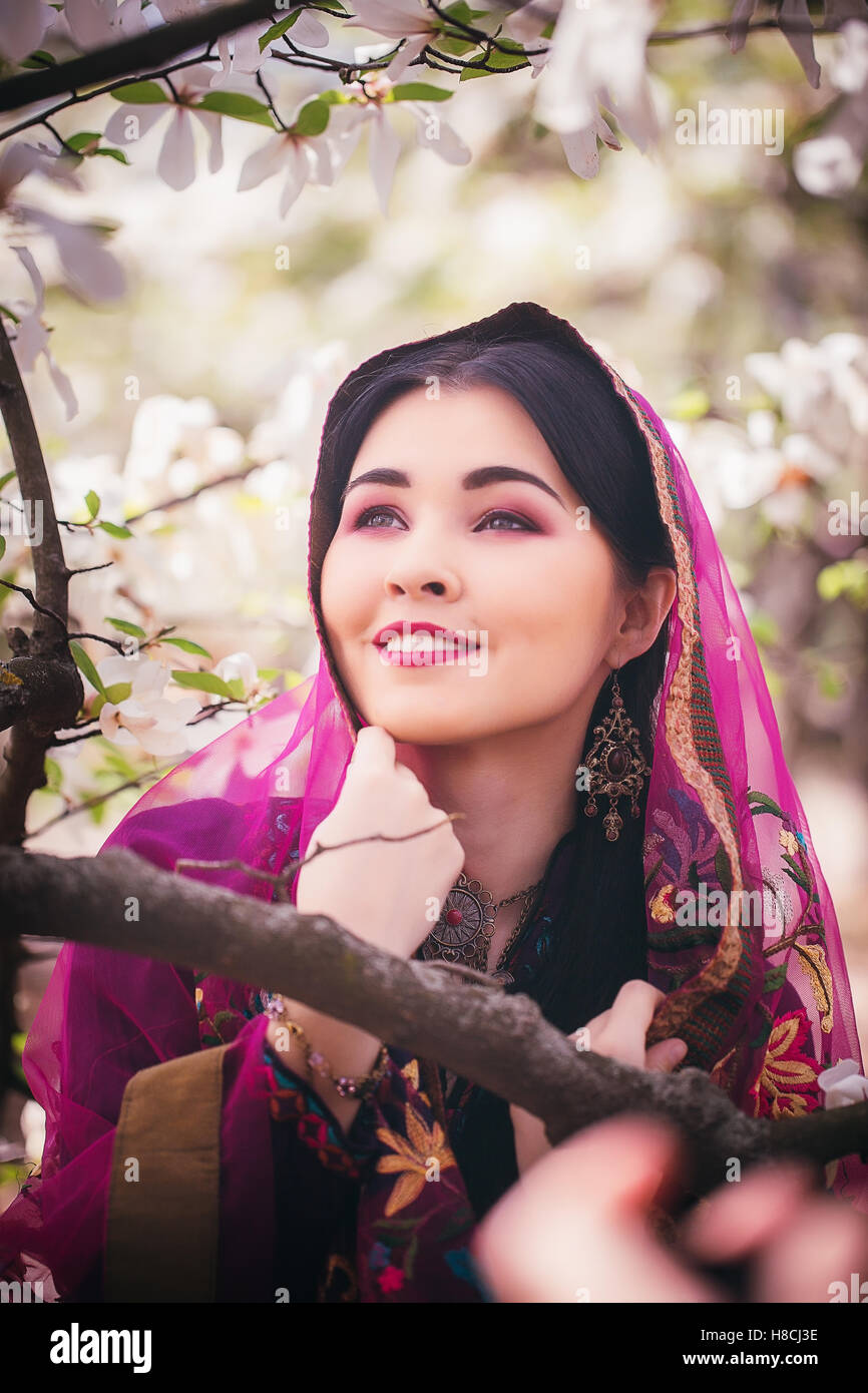 Beautiful young Asian woman looks into the distance. In the garden of ...