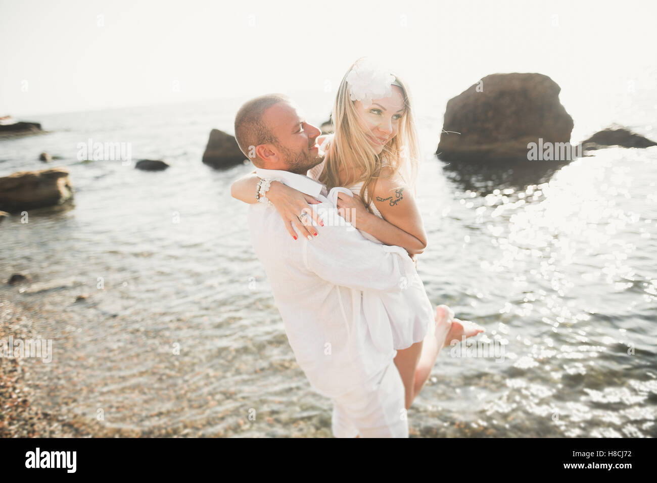 Wedding couple kissing and hugging on rocks near blue sea Stock Photo ...
