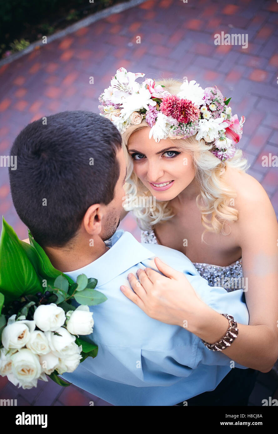 Pretty couple hugging and flirting in an urban park a wreath on his ...