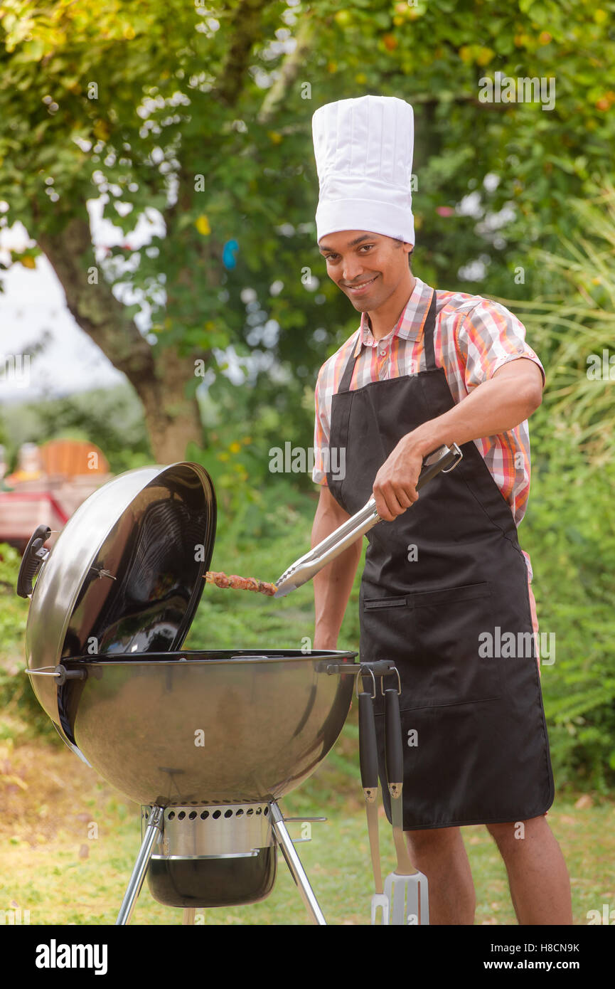 Handsome man preparing barbecue for friends, France Stock Photo - Alamy