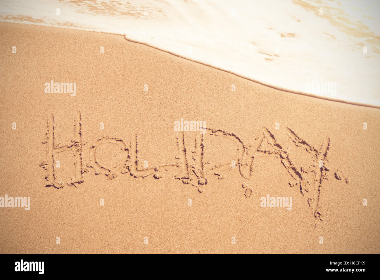 Holiday text on sand at beach Stock Photo - Alamy
