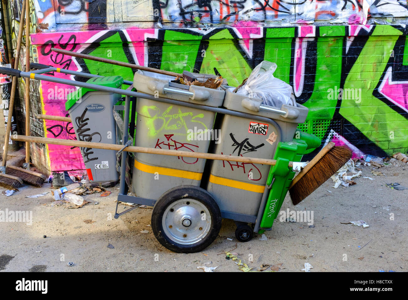 Council refuse cart in front of graffiti painted wall, London, UK Stock ...