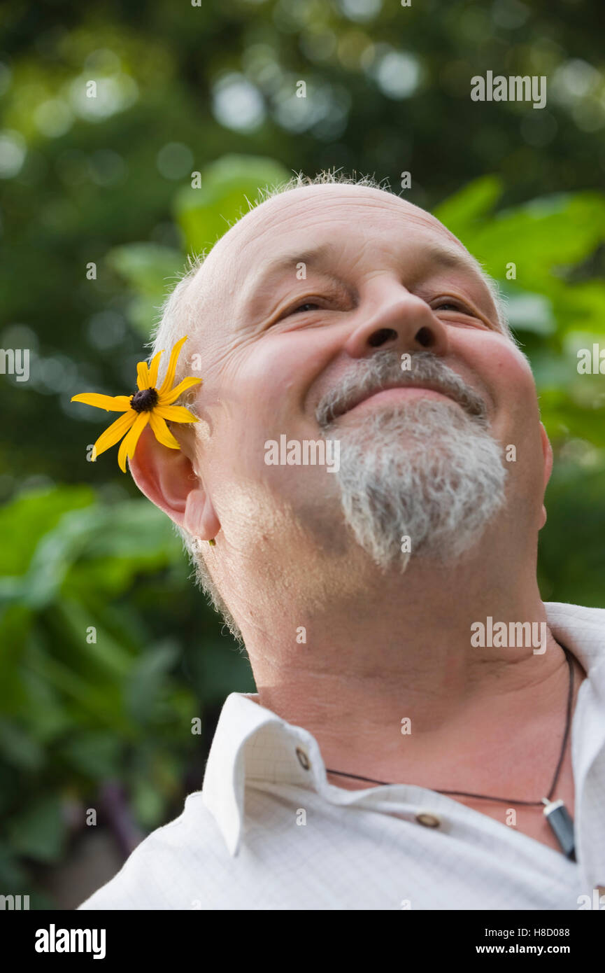Smiling elderly man with flower behind his ear Stock Photo - Alamy