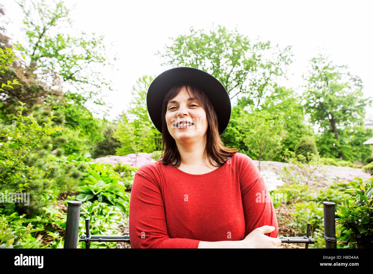 Mature Brunette Woman In Green Garden Wearing Hat Smiling Frie Stock