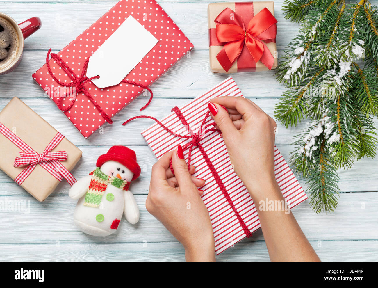 Female hands wrapping christmas gift box above wooden table. Top view ...
