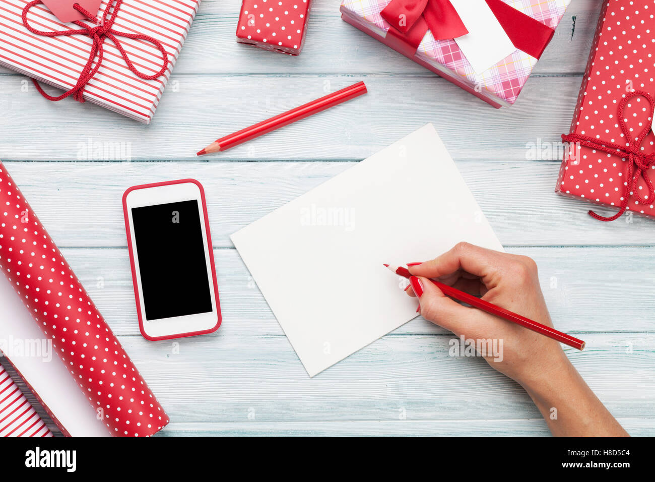 Female writing greeting card and wrapping christmas gifts. Top view ...