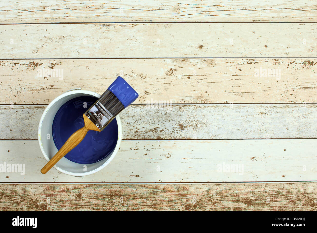 Loaded paintbrush placed across a white paint kettle filled with dark ...