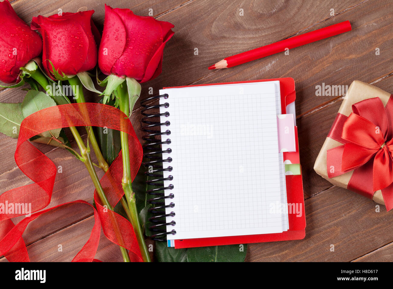 Love letter notepad, red roses and gift box on wooden table. Valentines ...