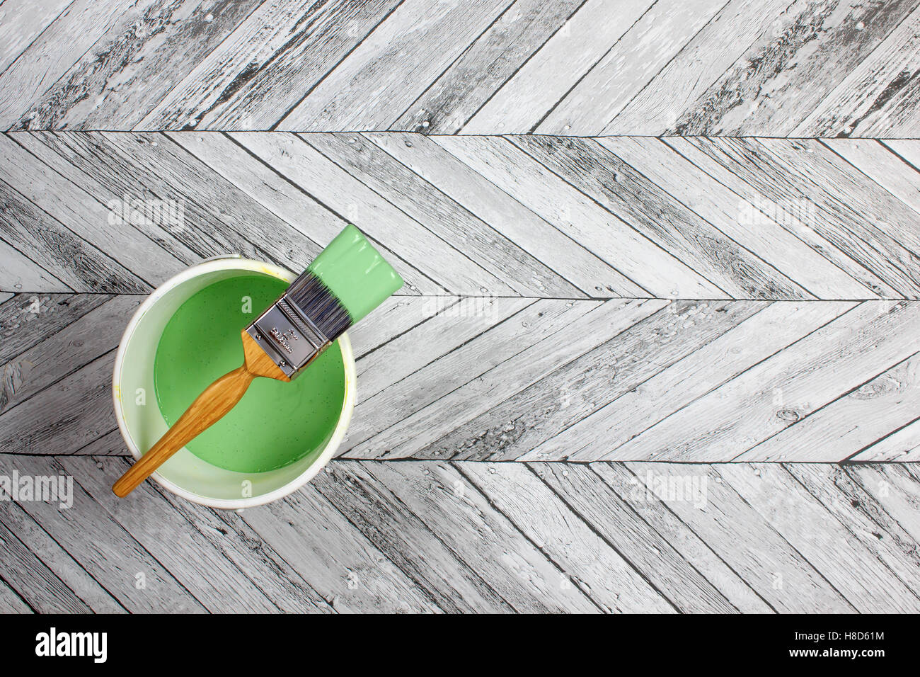 Paintbrush placed across a white paint kettle filled with green paint ...