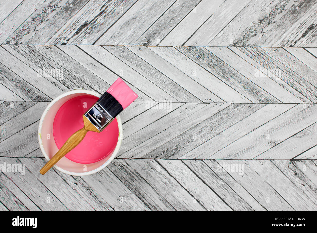 Loaded paintbrush placed across a white paint kettle filled with pink ...