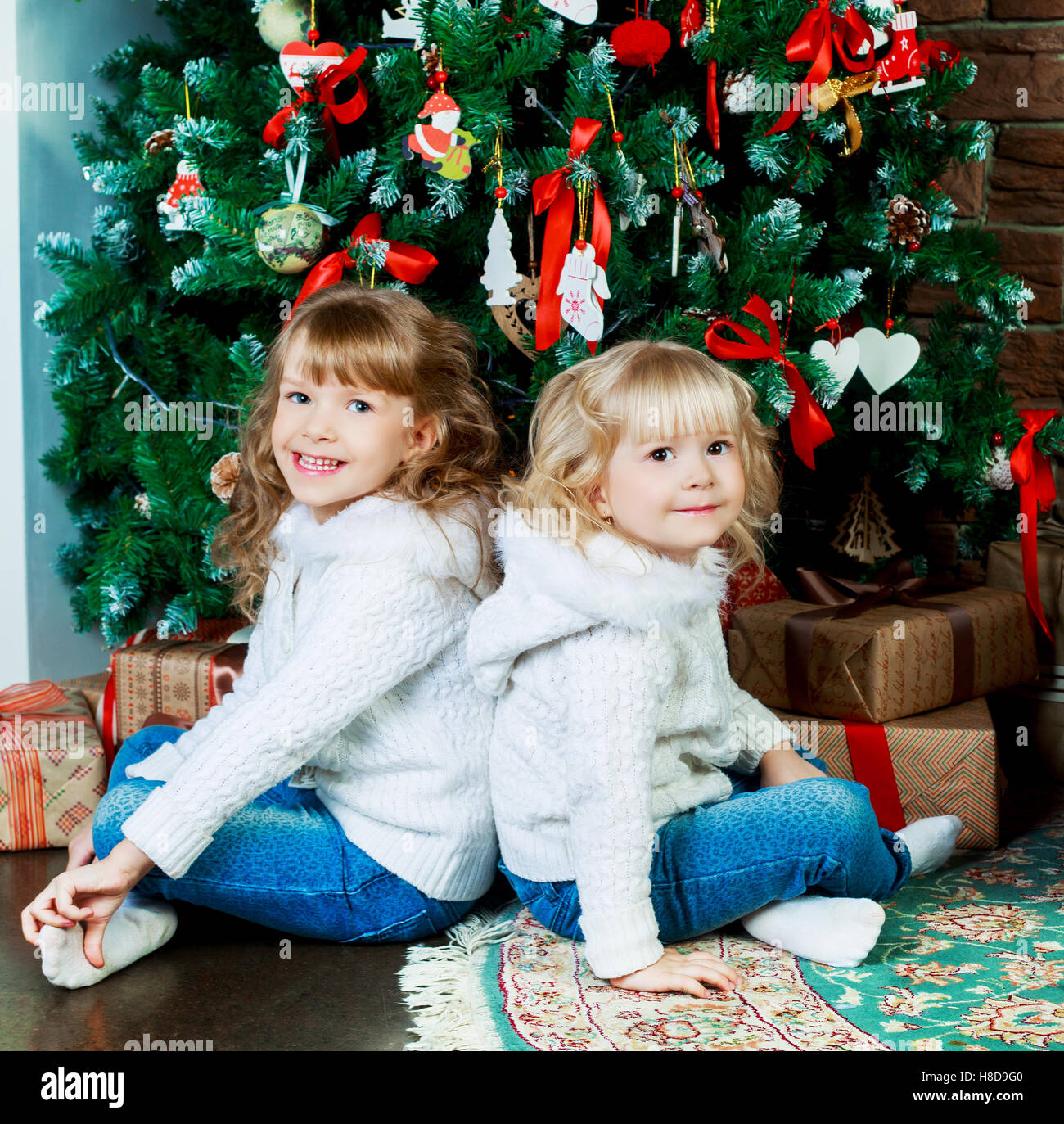 two happy sisters at home with Christmas tree Stock Photo - Alamy