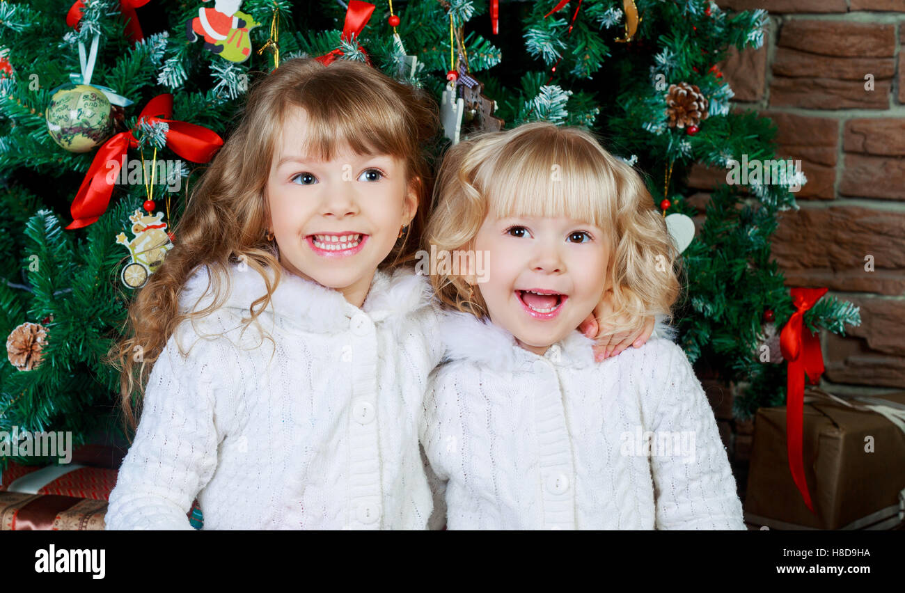 two happy sisters at home with Christmas tree Stock Photo - Alamy