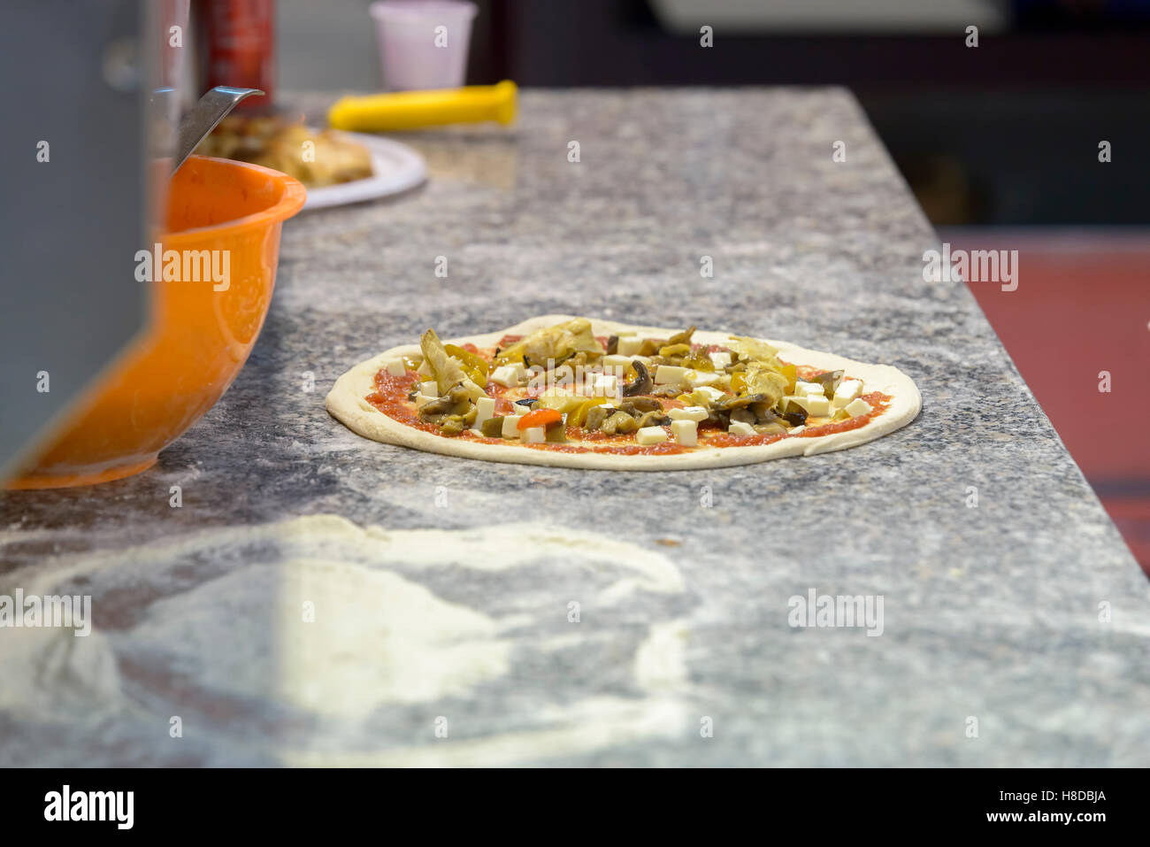 uncooked pizza on a marble kitchen with mozzarella and vegetables Stock ...