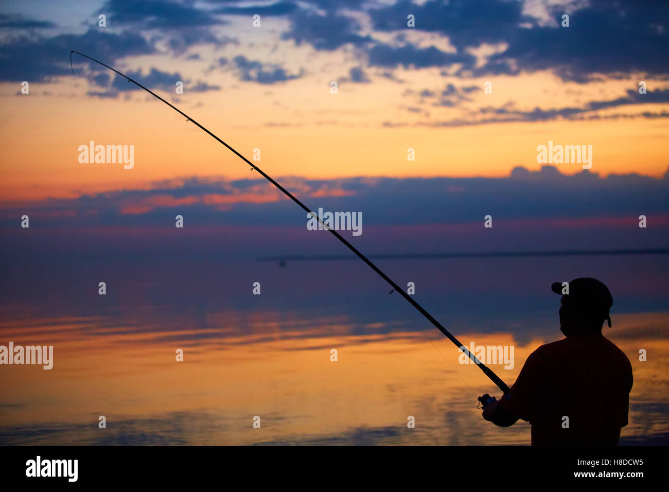 Silhouette of fishermen on quiet ocean with rays sunset Stock Photo - Alamy