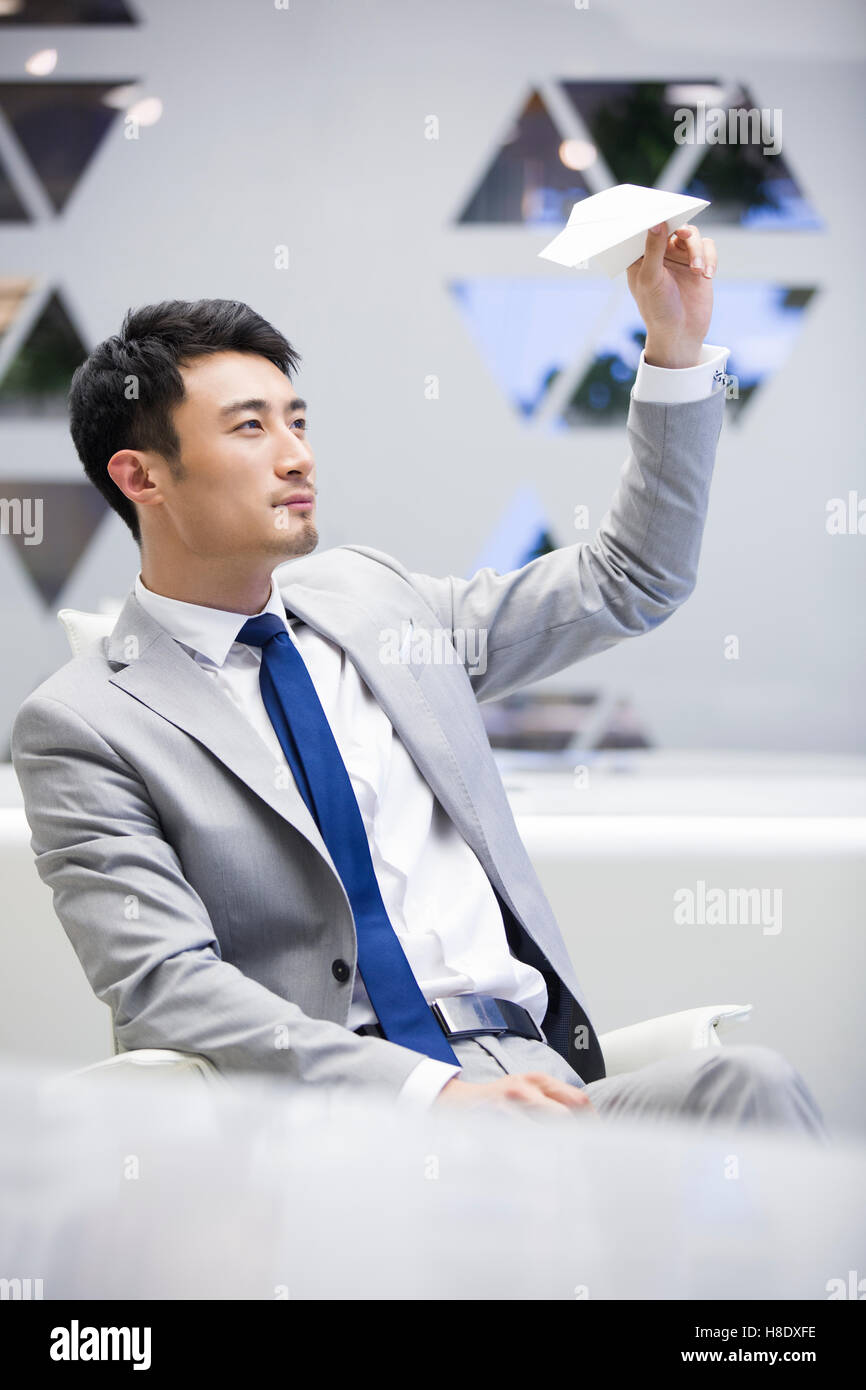 Young Chinese businessman flying a paper airplane Stock Photo - Alamy