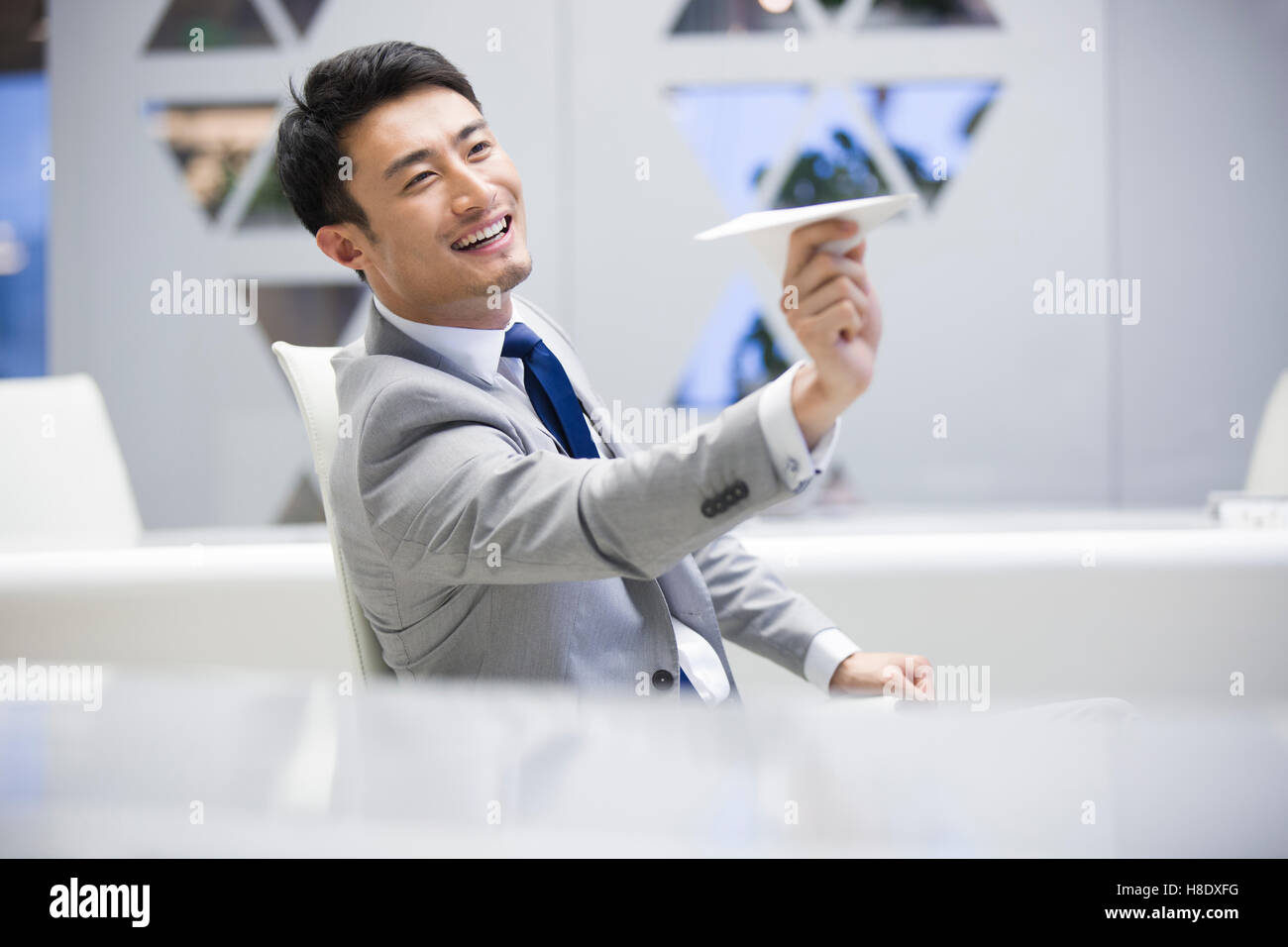 Young Chinese businessman flying a paper airplane Stock Photo - Alamy